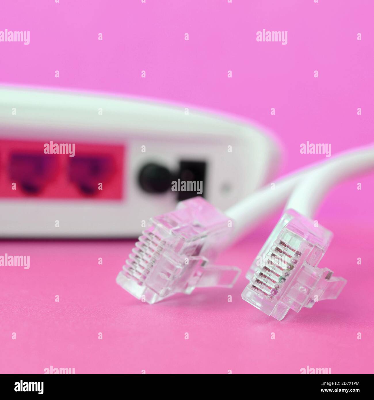 Internet router and Internet cable plugs lie on a bright pink ...