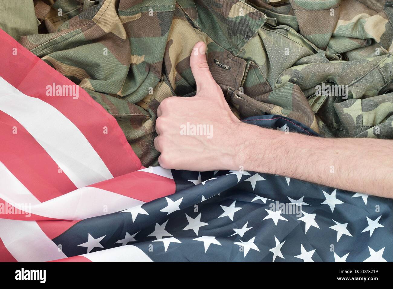 Hand shows thumbs up on american flag and military uniform. Concept of ...