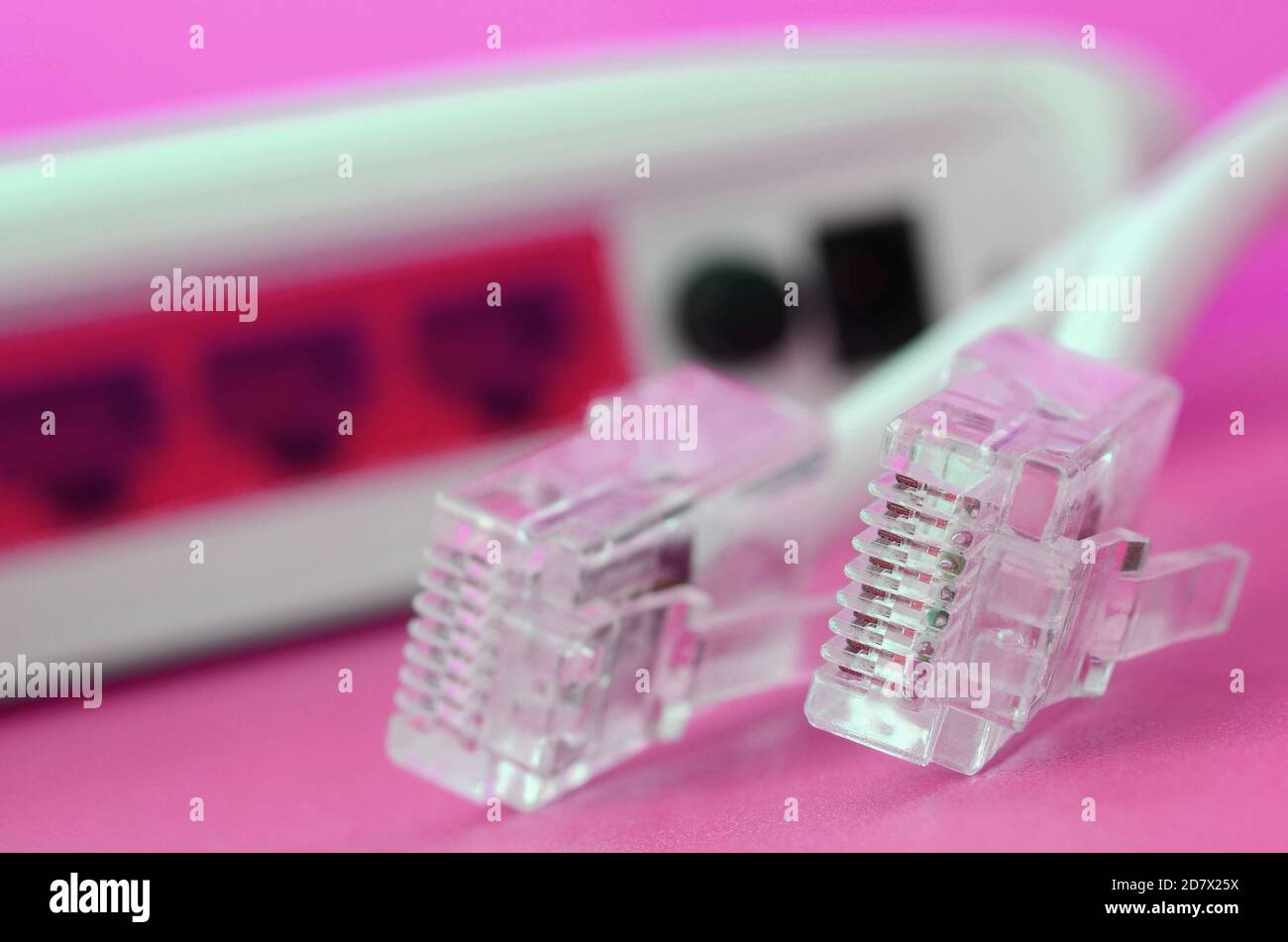 Internet router and Internet cable plugs lie on a bright pink ...