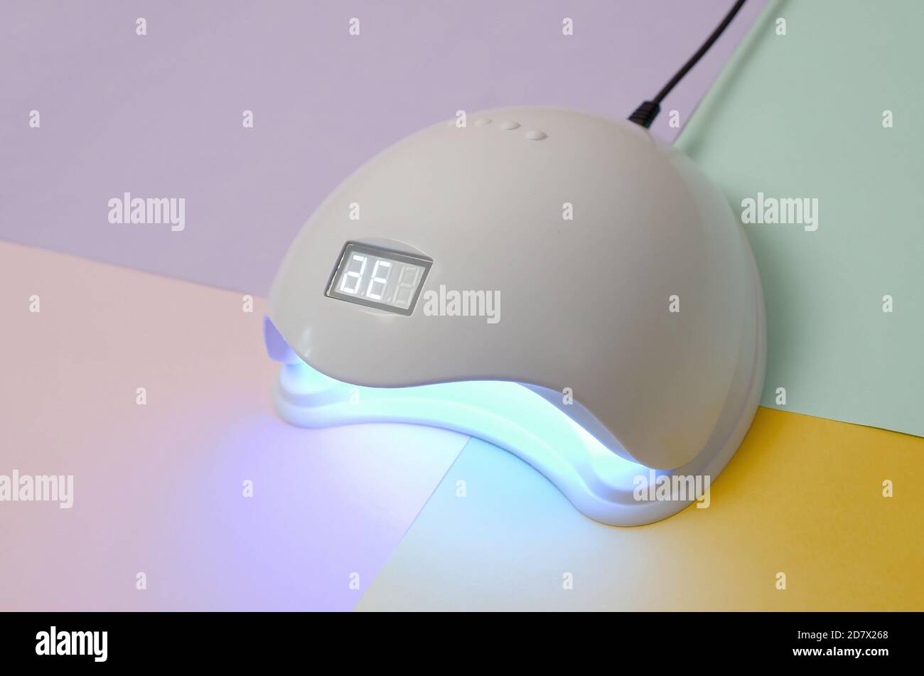 UV LED nail lamp for curing process by gel method lies on pastel multi ...
