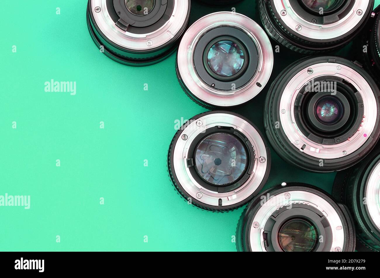 Several photographic lenses lie on a bright turquoise background. Space ...