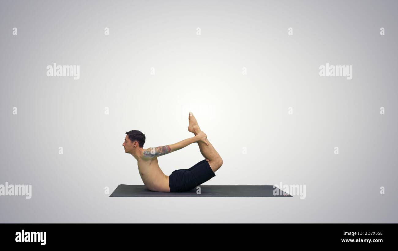 Sporty muscular young yogi man doing backbend exercise, dhanuras Stock ...