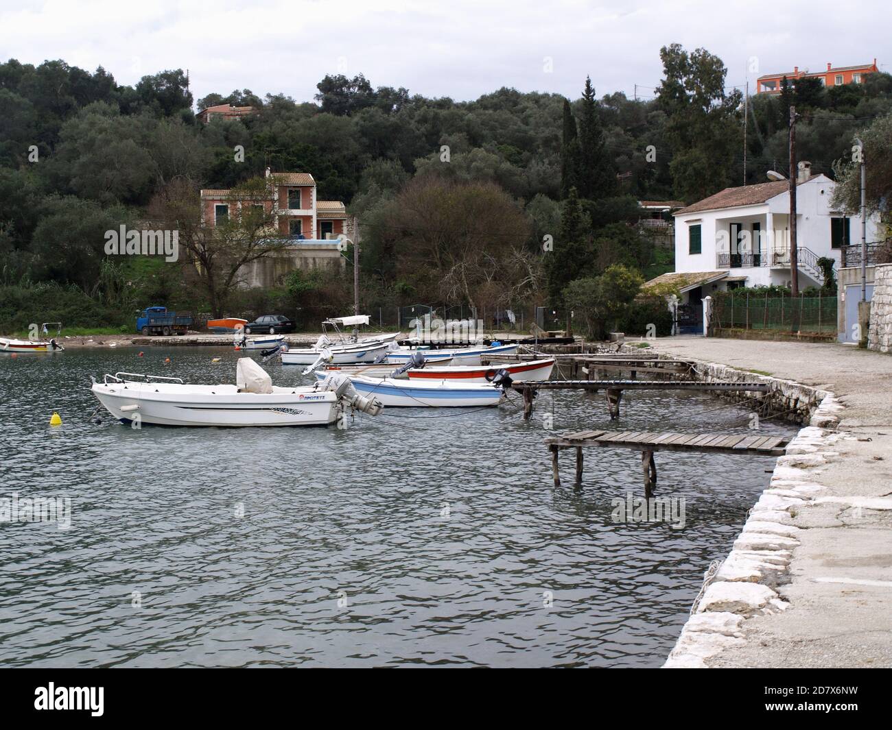 Boats moored to wooden jetties the traditional Greek village harbour of ...
