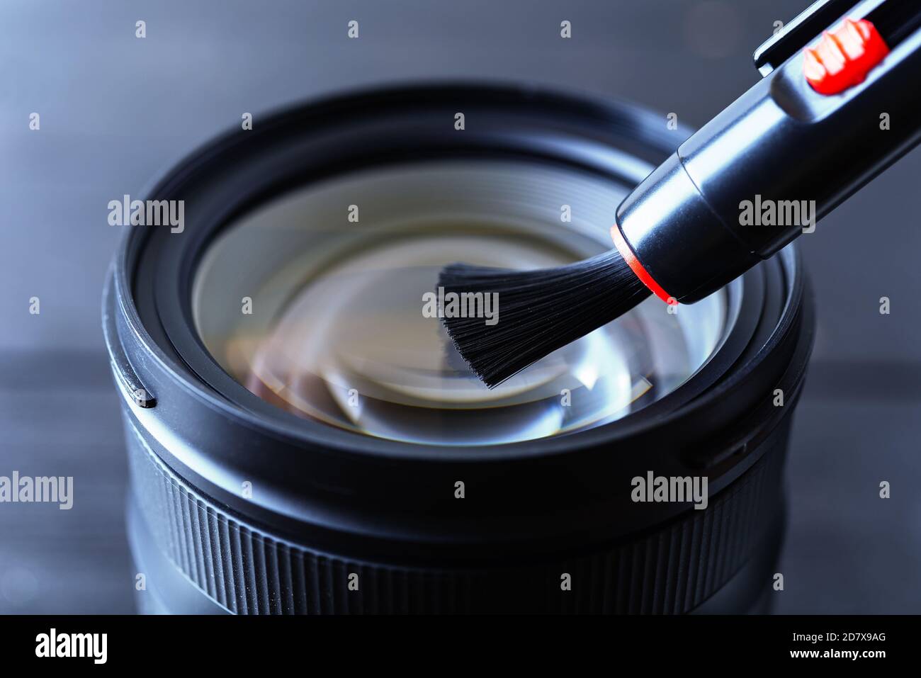 Sweeping dust from front lens using lens pen brush. Routine removal of ...