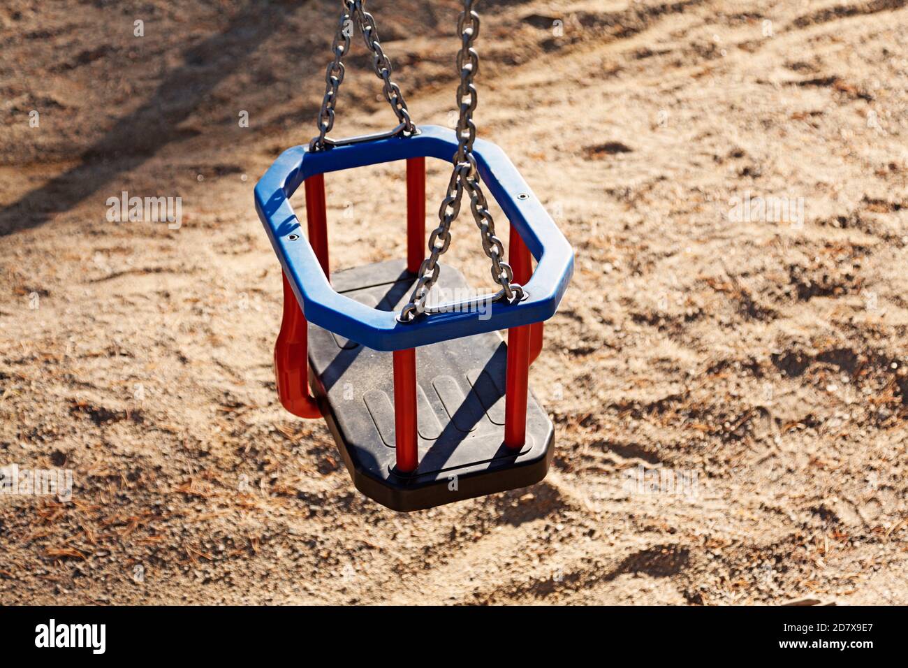 a blue and red swing in the sandbox Stock Photo - Alamy