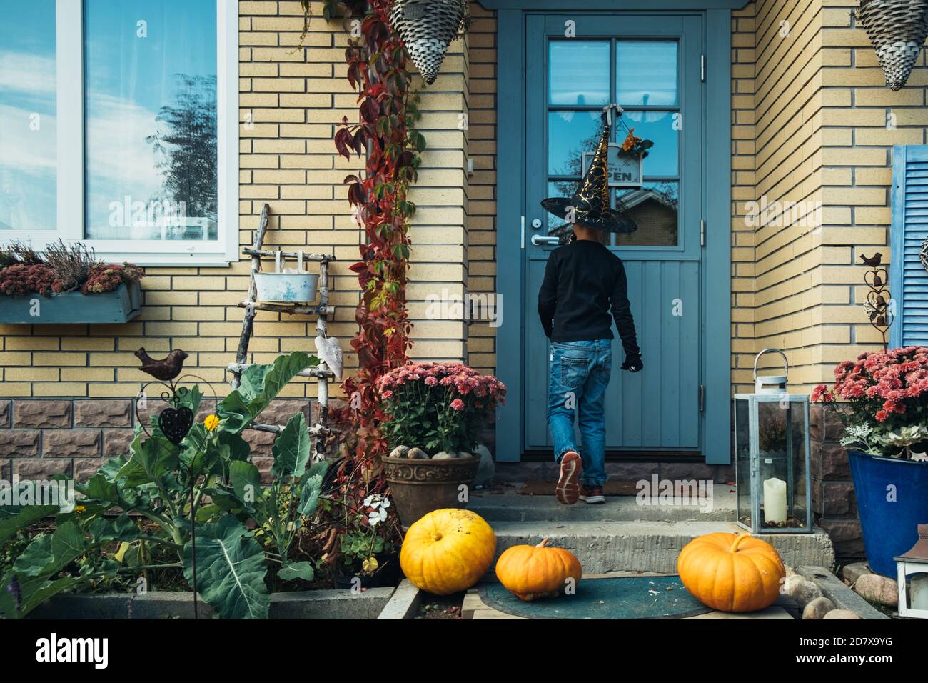 The boy knocking at the beautiful house with pumpkins in costumer hats ...