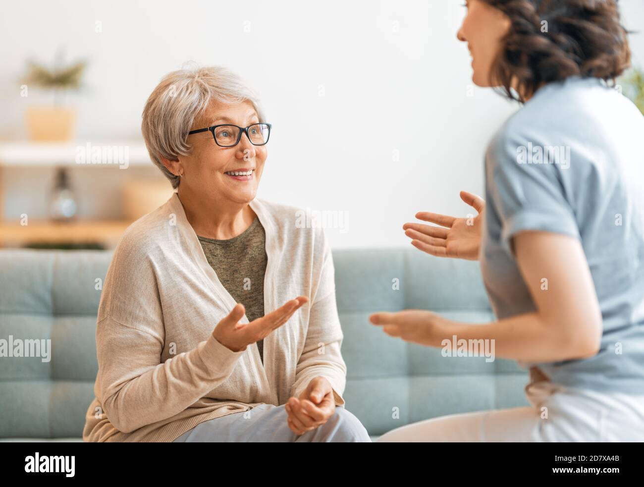 Beautiful mother and daughter are talking and smiling while sitting on ...