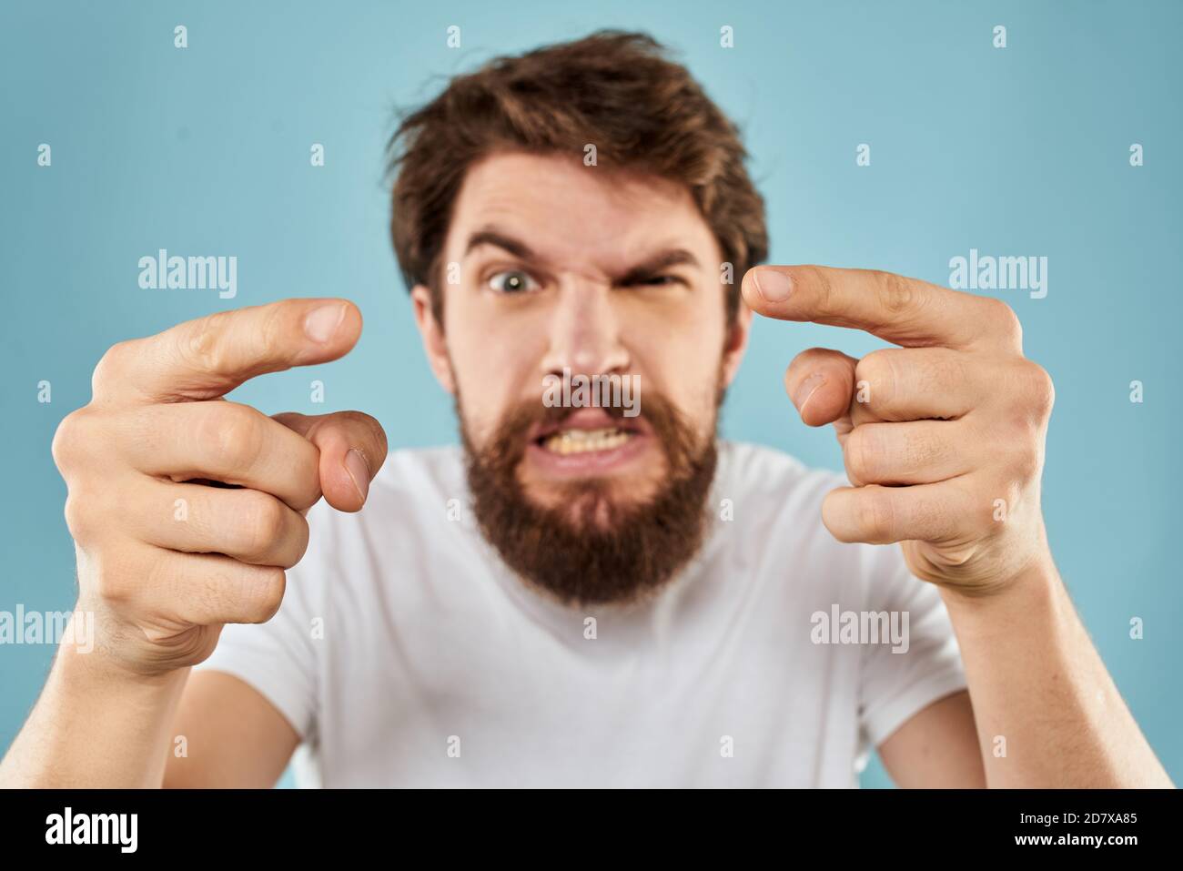 Bearded man in white T-shirt emotions gestures with hands displeased ...