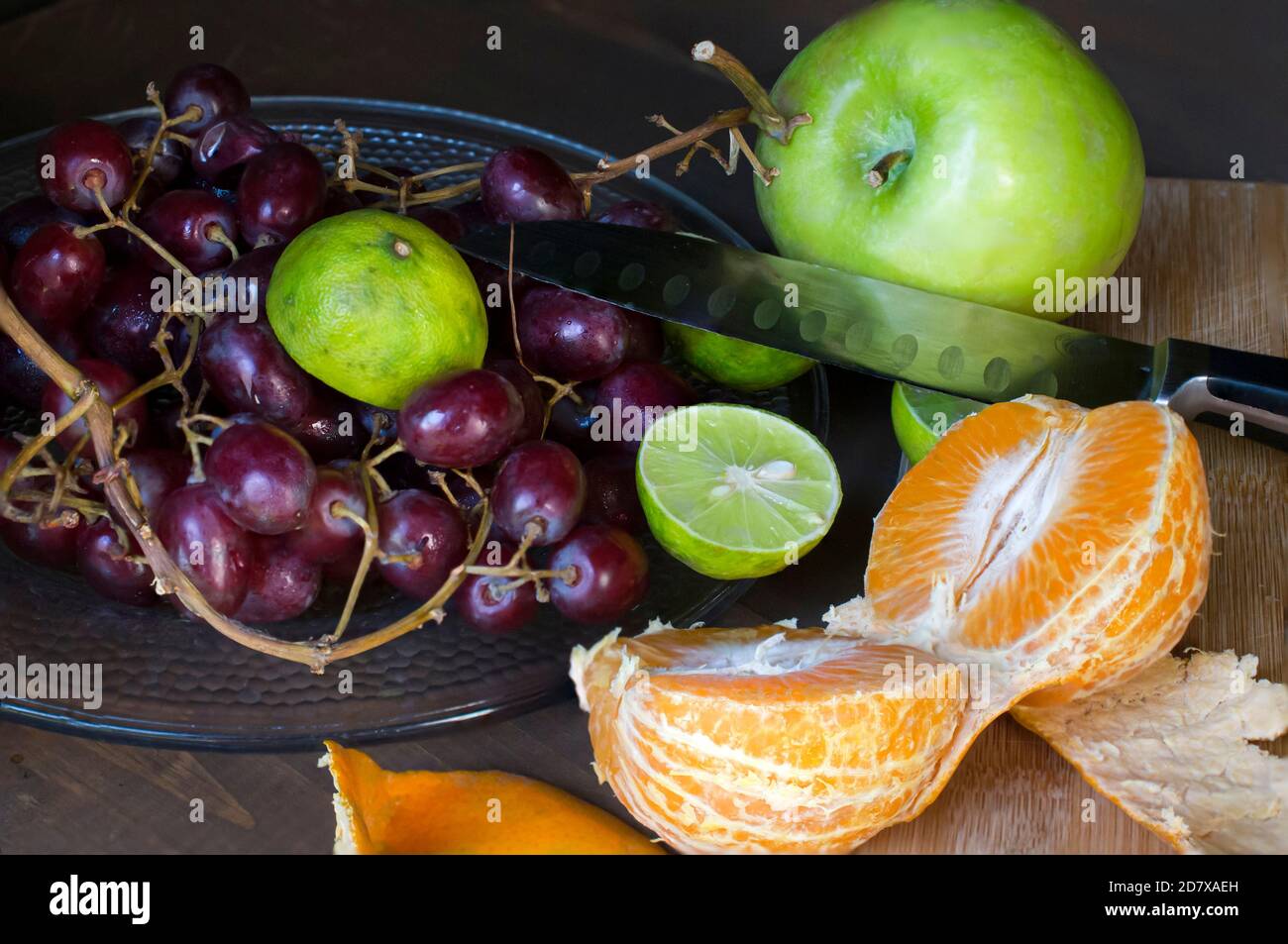 close up of fruit on a cutting board with grapes lemon, green apple and ...