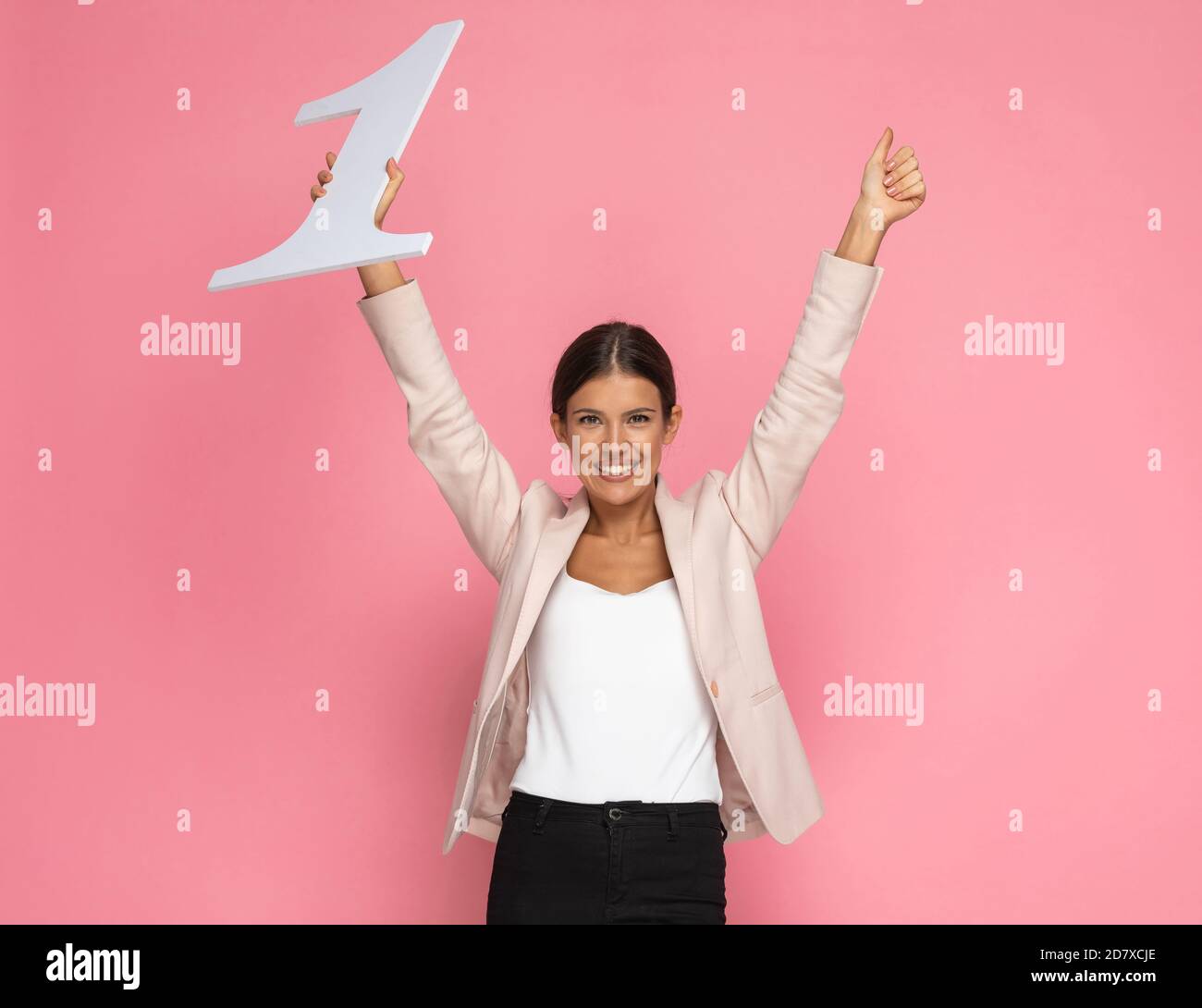 beautiful businesswoman holding a number one and giving a thumbs up in ...