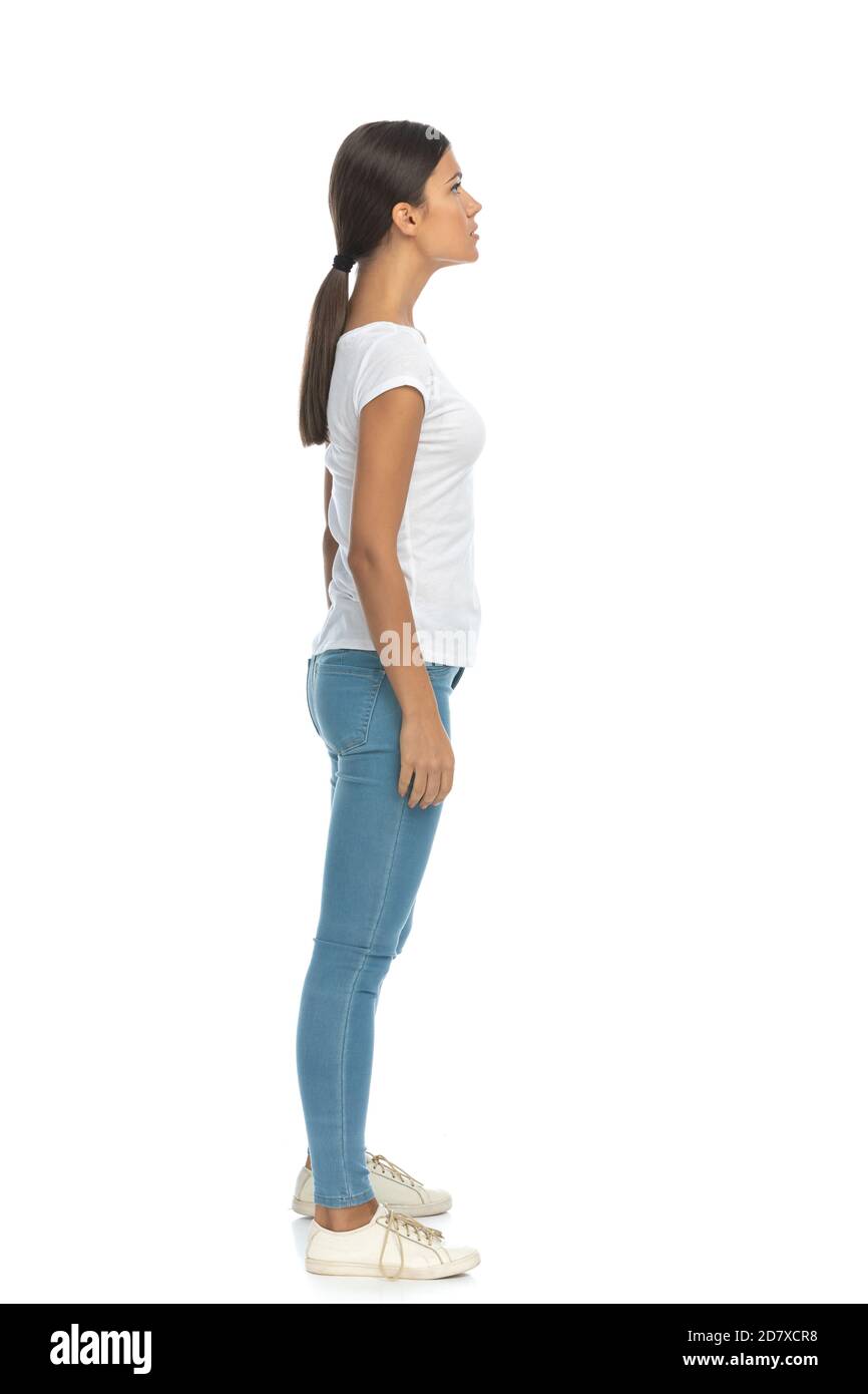 Side view of focused casual woman looking forward, standing on white ...
