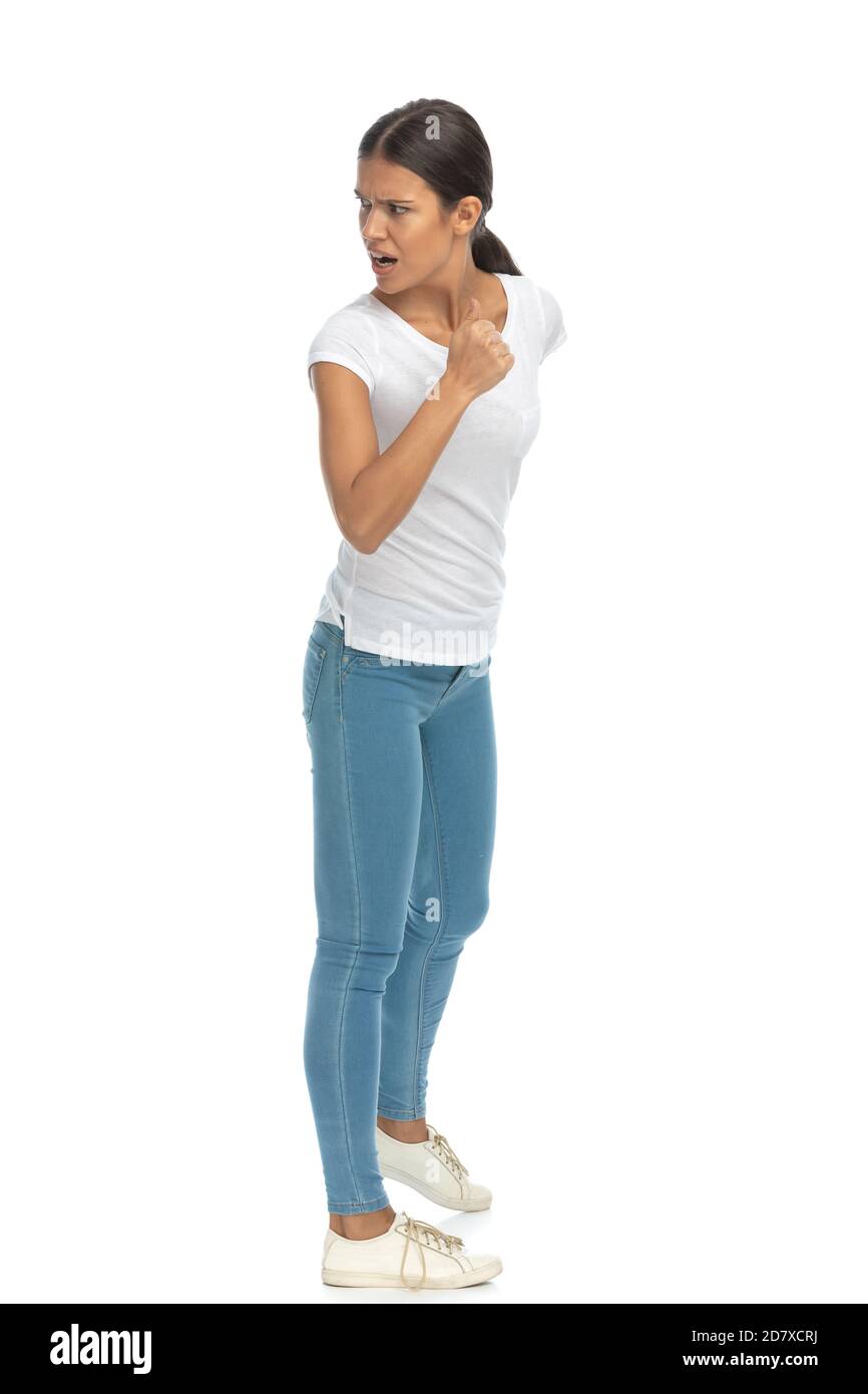 Side view of outraged casual woman looking over shoulder and shouting ...