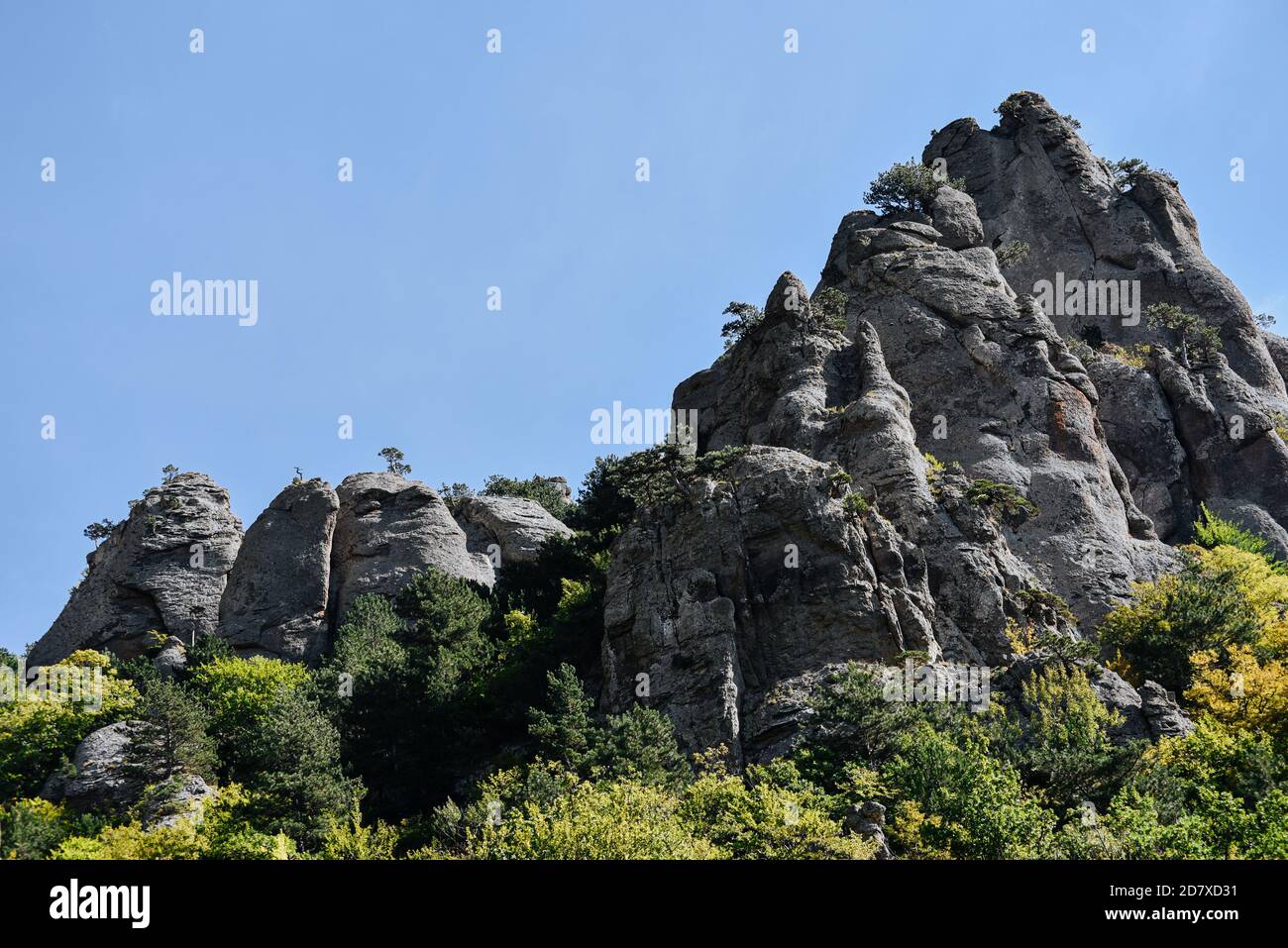 Stone hills and mountains with green trees and bushes against the blue ...