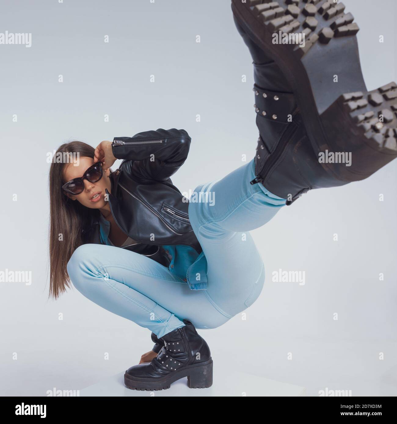 Tough fashion model holding sunglasses and kicking with her leg ...