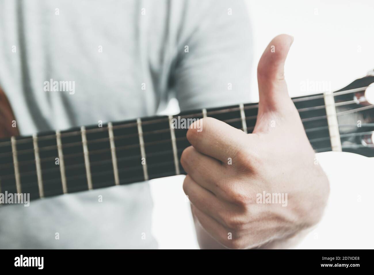 Close-up of man showing thumbs up on guitar fretboard because something ...