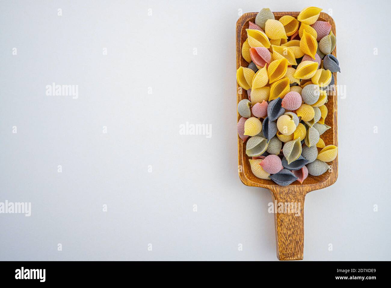 Italian uncooked colored pasta in the shaped of seashells with yellow ...