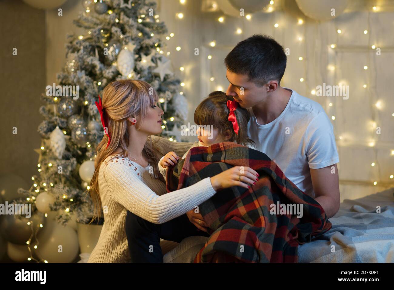 Cozy Christmas Morning. Young family on background of Christmas lights ...