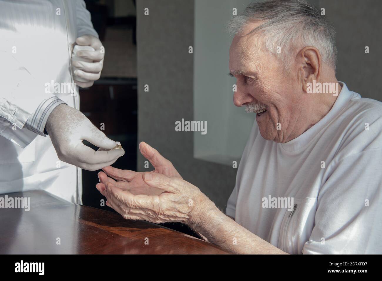 doctor gives a pill to an old man. The old man is ill and needs ...