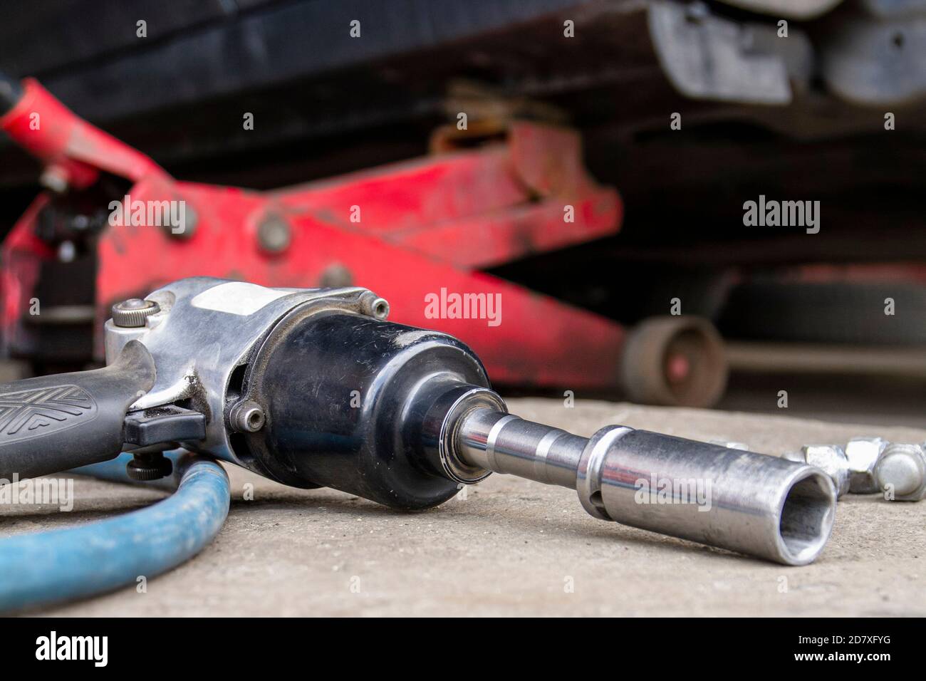 Pneumatic wrench tool on the asphalt and a car jack for lift up the ...