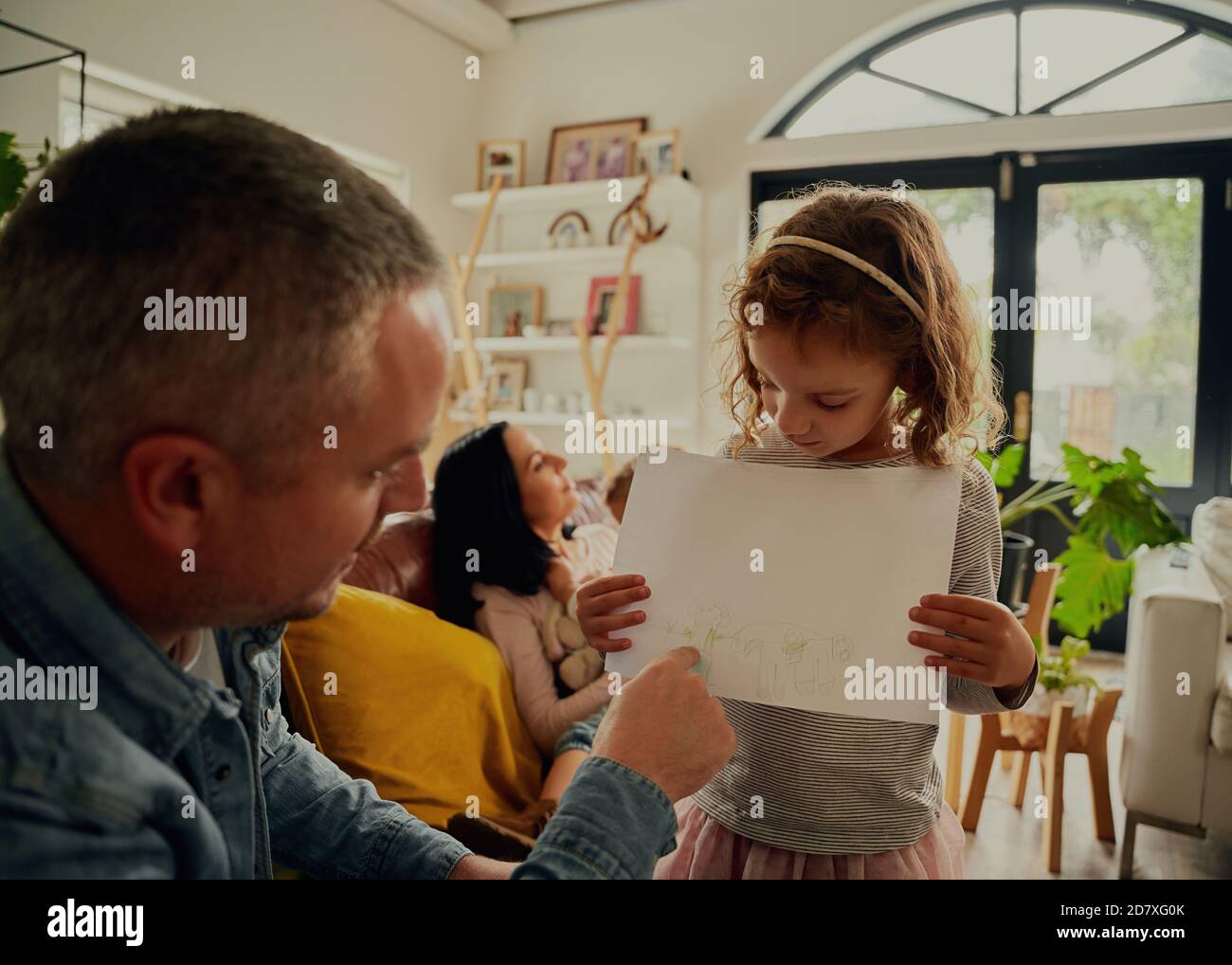 Creative daughter showing drawing on paper to father asking for ...