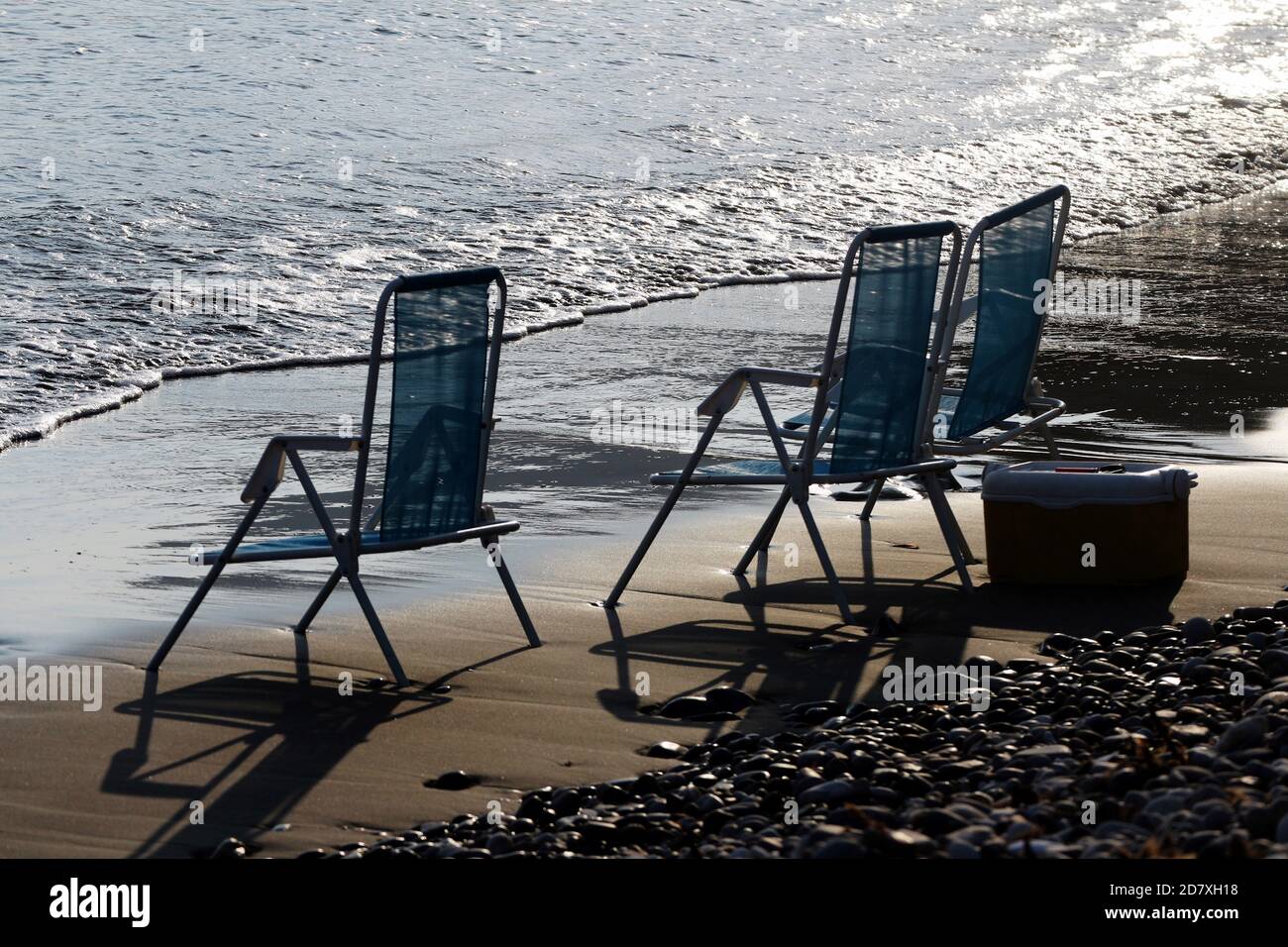 Three empty deck chairs on the beach edge Stock Photo - Alamy
