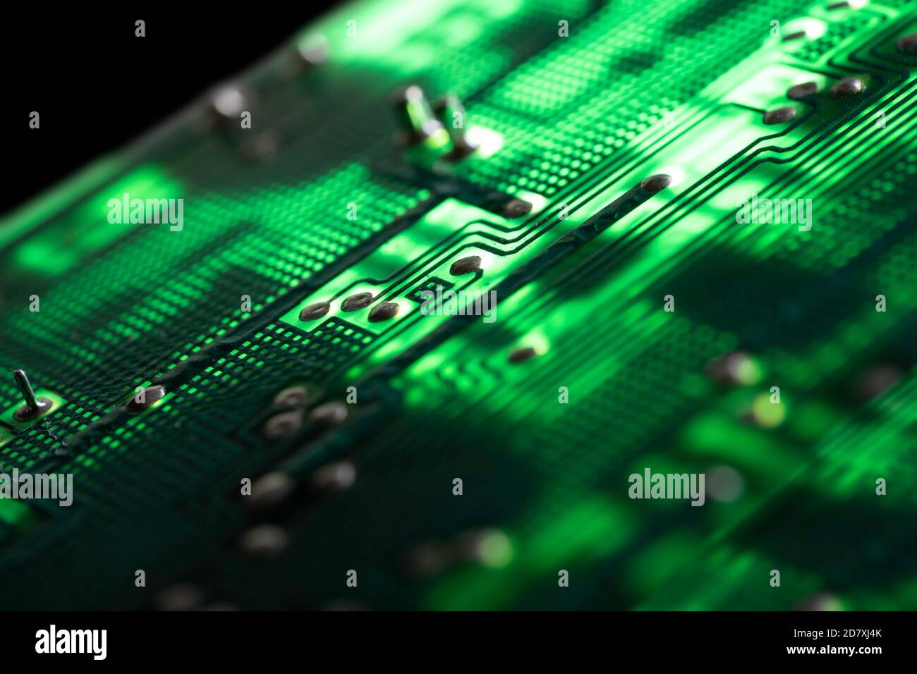 Detail of an illuminated green electronic circuit board with many ...
