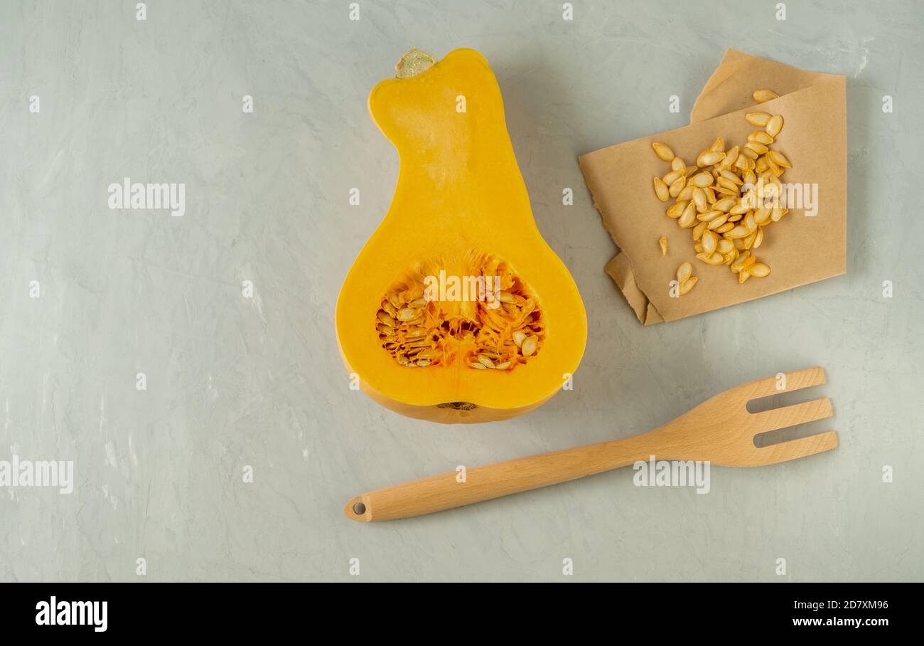 Composition of half ripe pumpkin with seeds on parchment and a wooden ...