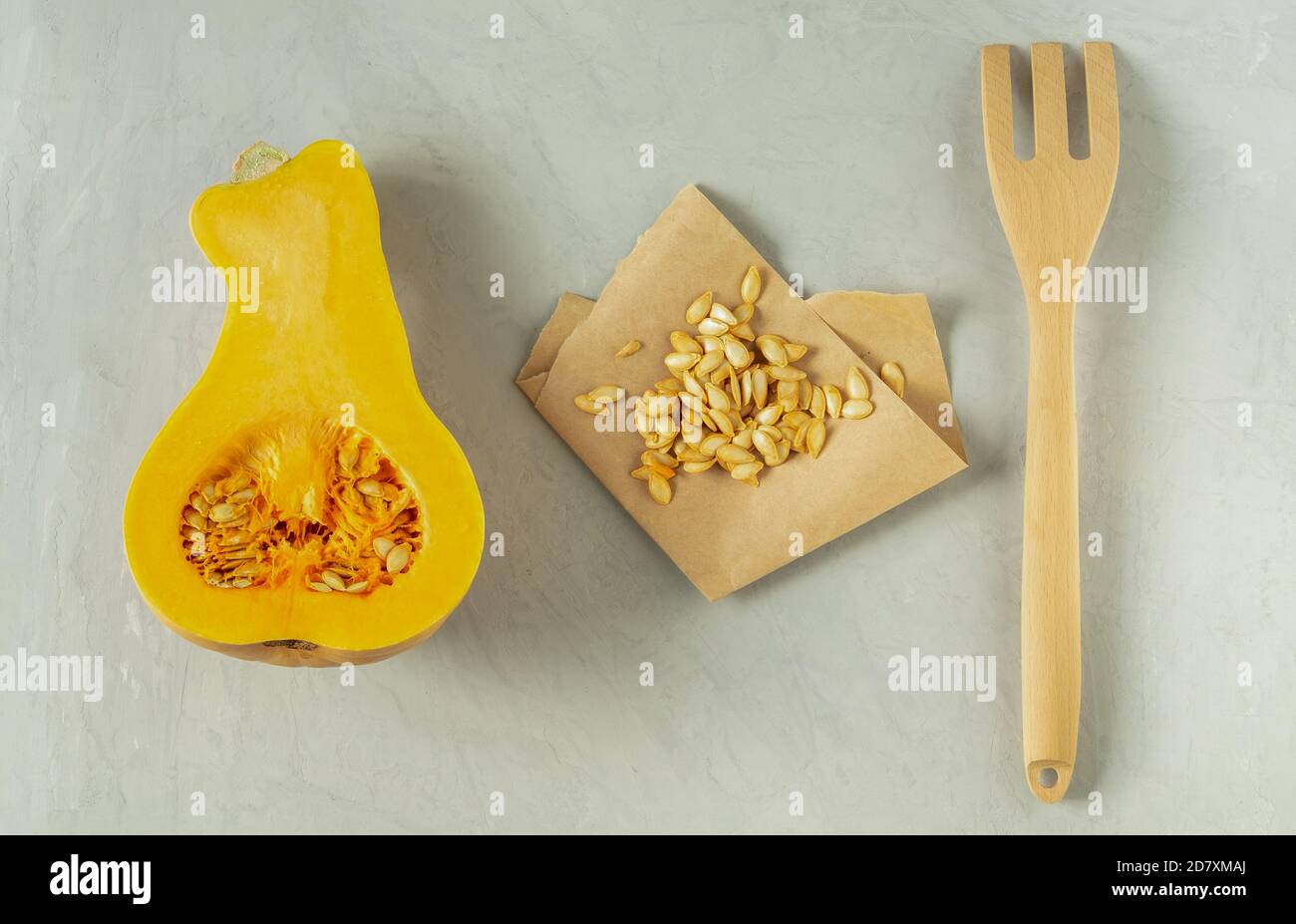 Composition of half ripe pumpkin with seeds on parchment and a wooden ...