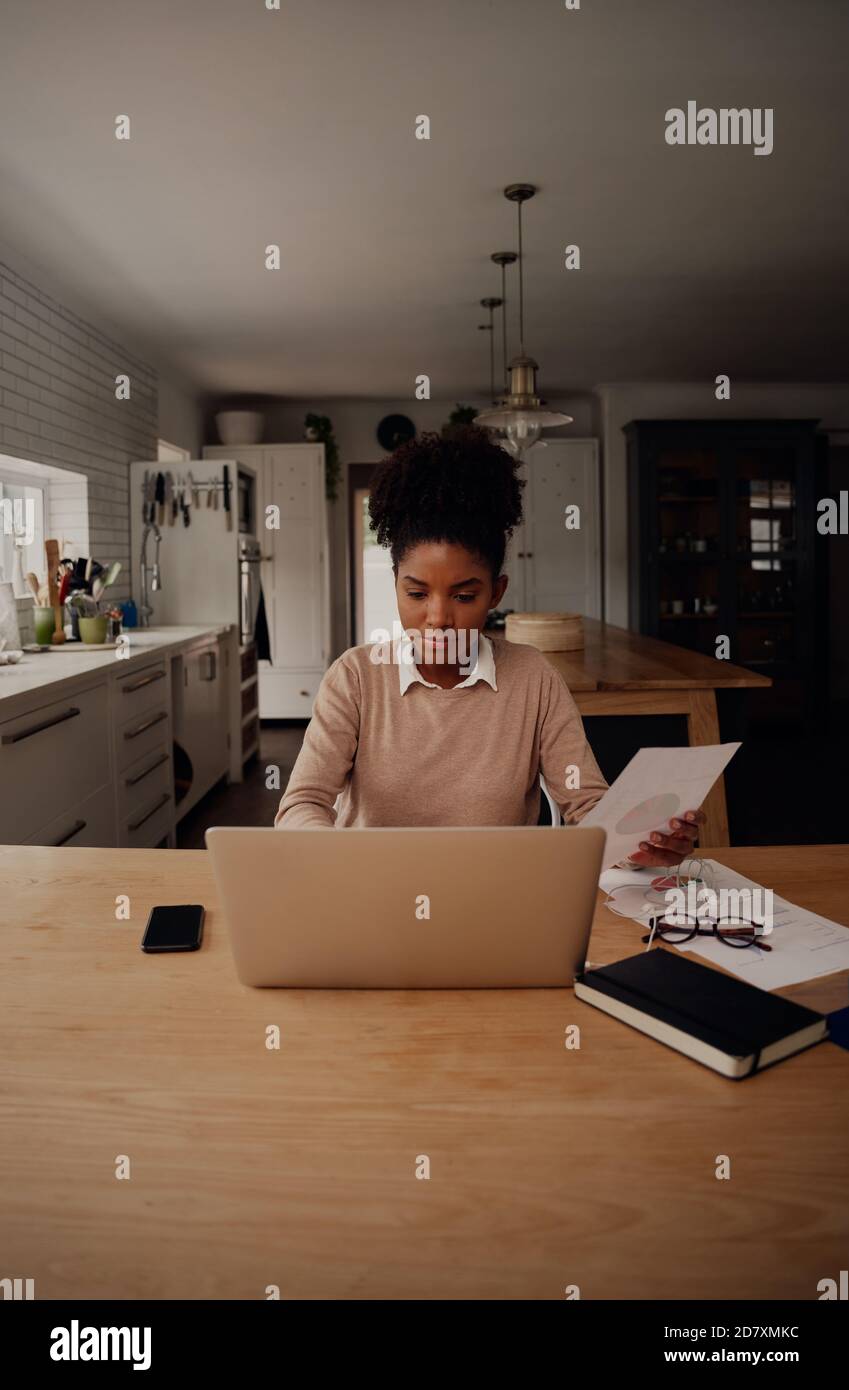 Concentrated young entrepreneur working on laptop with help of graph ...