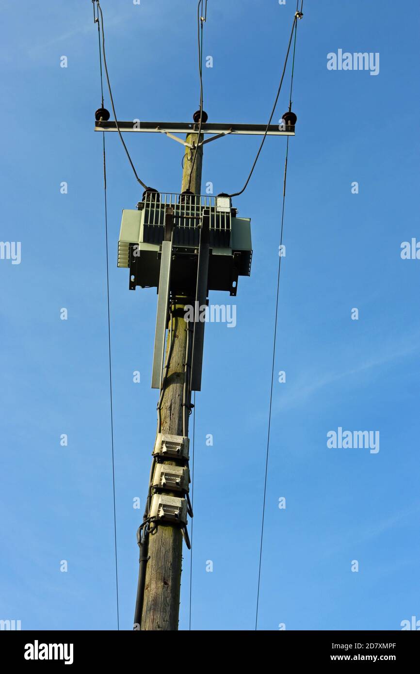 Electricity pole transformer on a round wooden pole with cables and ...
