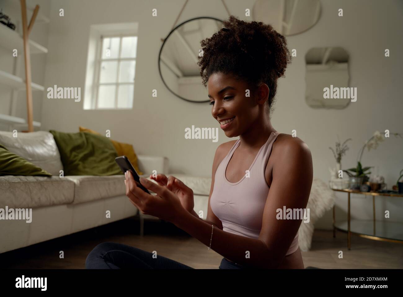 Happy young woman doing yoga and using cell phone sitting on the floor ...
