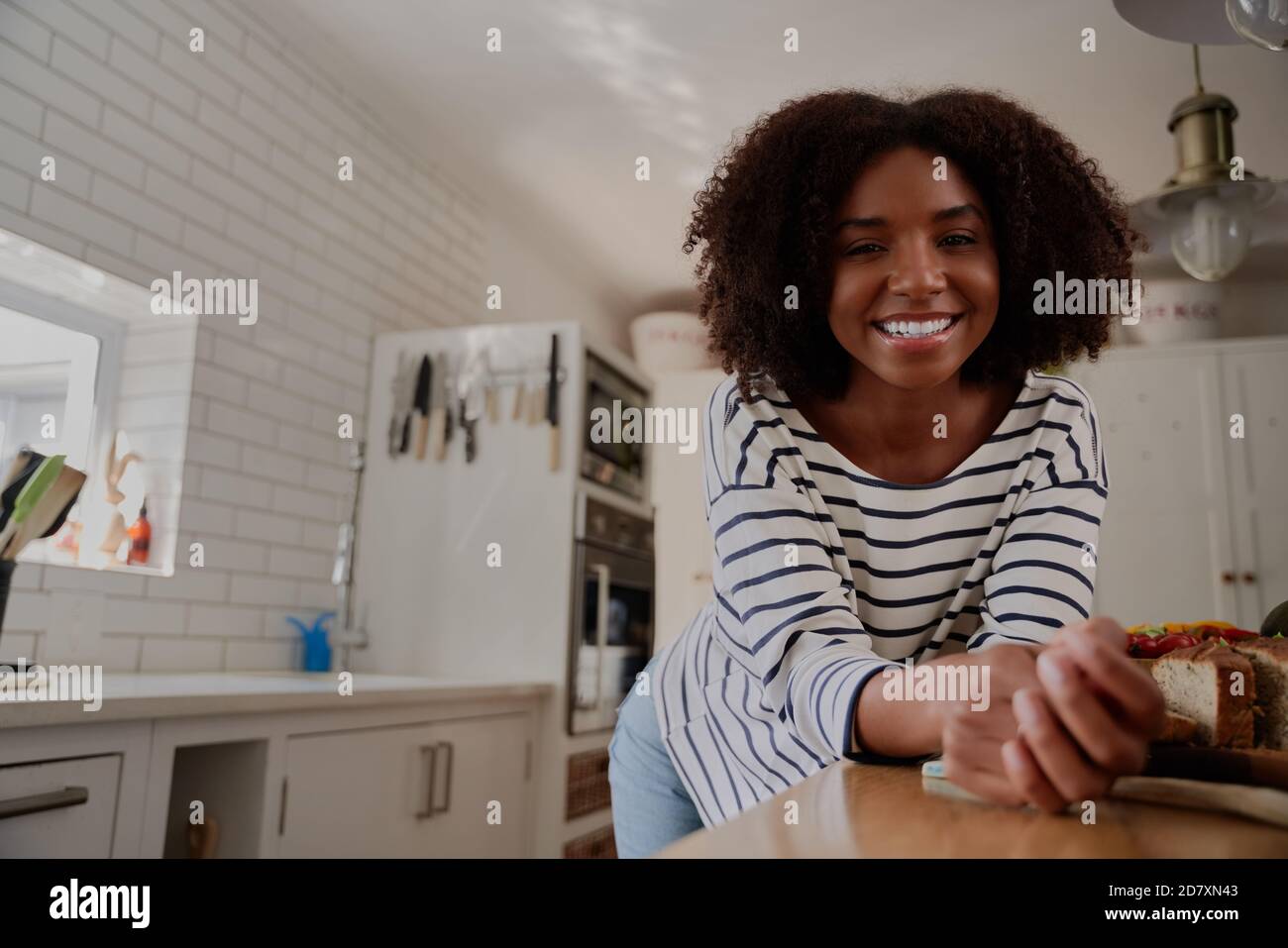 Happy woman standing in modern kitchen leaning on counter looking at ...