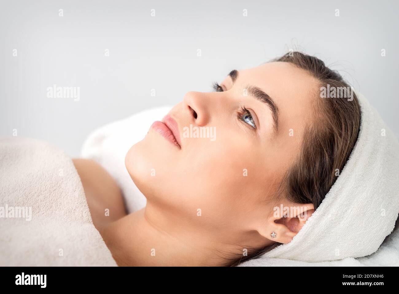 Side View Portrait Of Pensive Young Woman Lying On Beautician Table