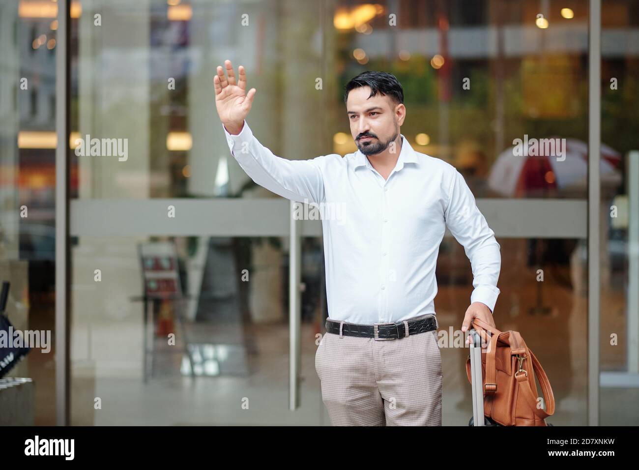 Hotel guest catchig taxi Stock Photo - Alamy