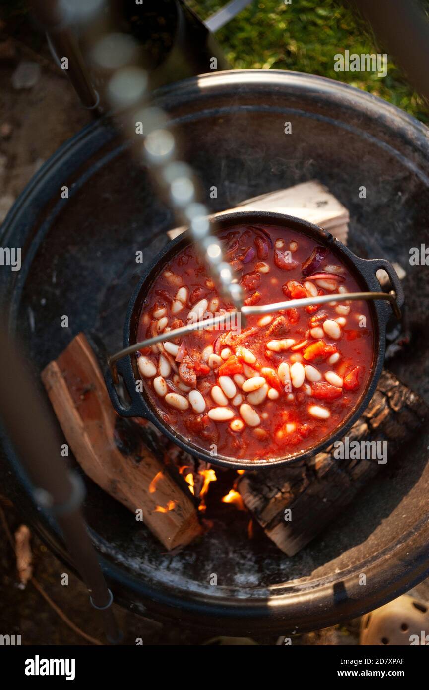 Spicy chorizo,bean,tomato and egg stew cooking over fire pit Stock ...