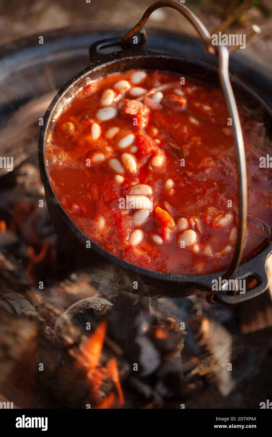 Spicy chorizo,bean,tomato and egg stew cooking over fire pit Stock ...