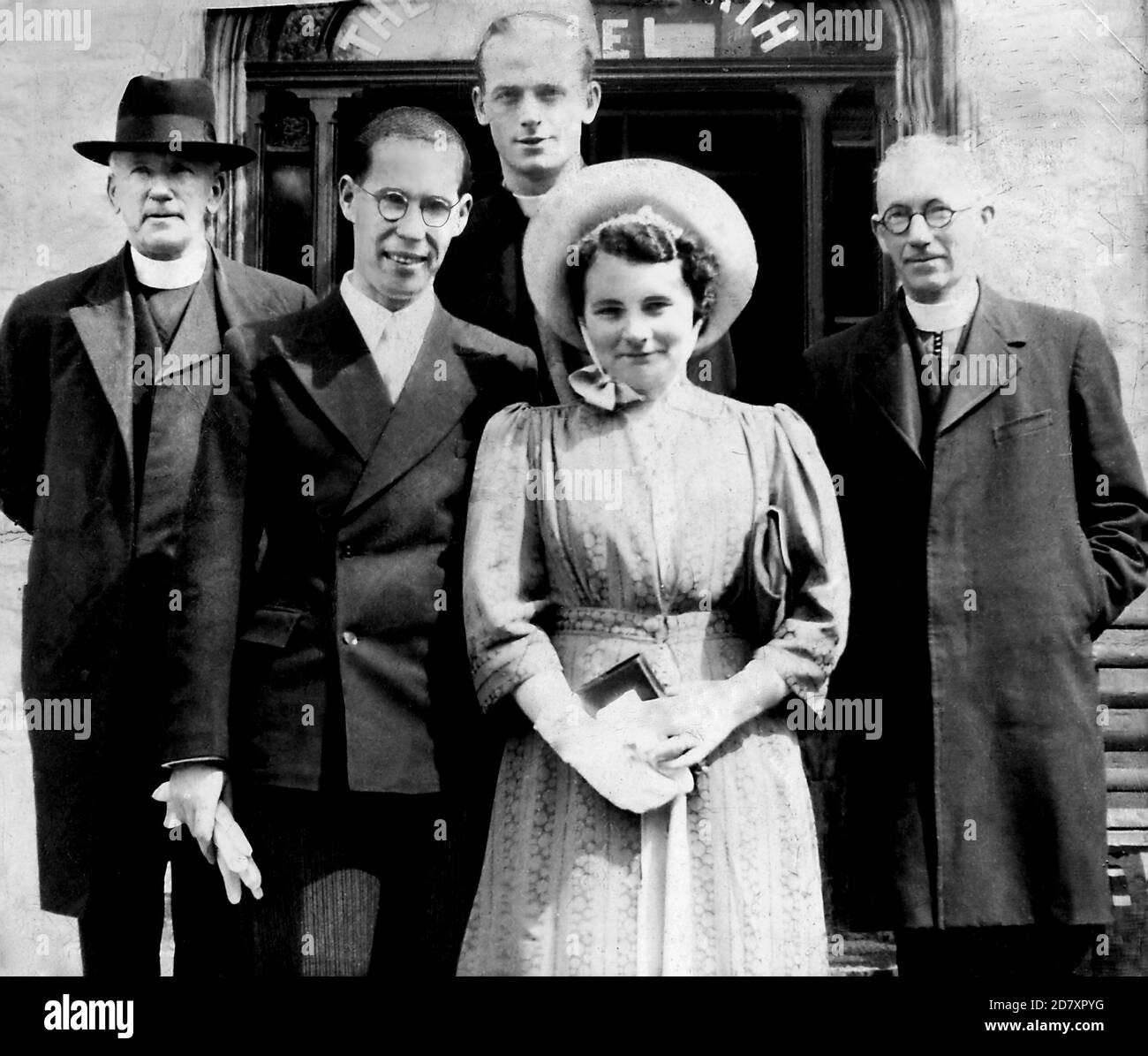 Newly married couple pose for a photograph with three priests outside ...