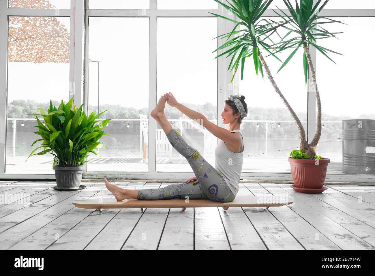 Woman stretching her leg on a indoor SUP board Stock Photo - Alamy