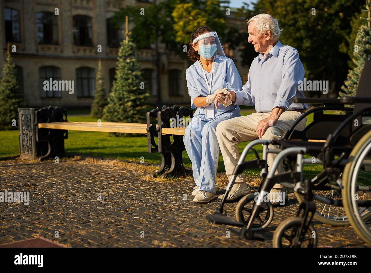 Young volunteer holding hands of smiling elderly man outdoors Stock ...
