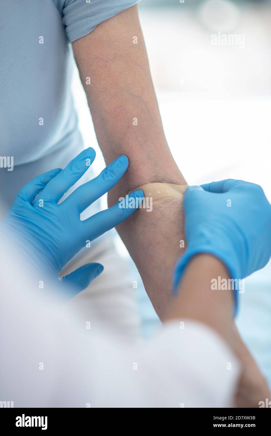 Close up picture of human hands putting plaster on a place of injection ...