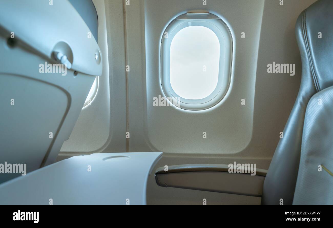 Plane window with white sunlight. Empty plastic airplane tray table at ...