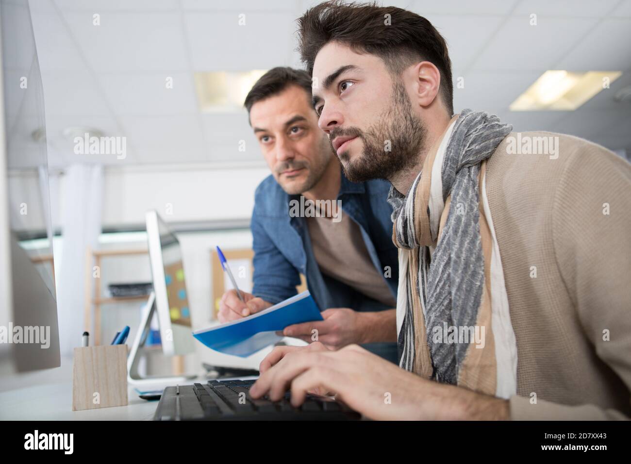 teacher looking over the shoulder of male student using computer Stock ...