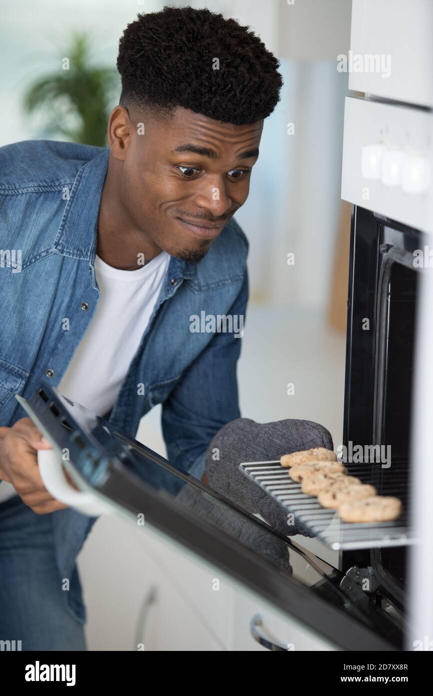 young man baking cookies in oven at home Stock Photo - Alamy