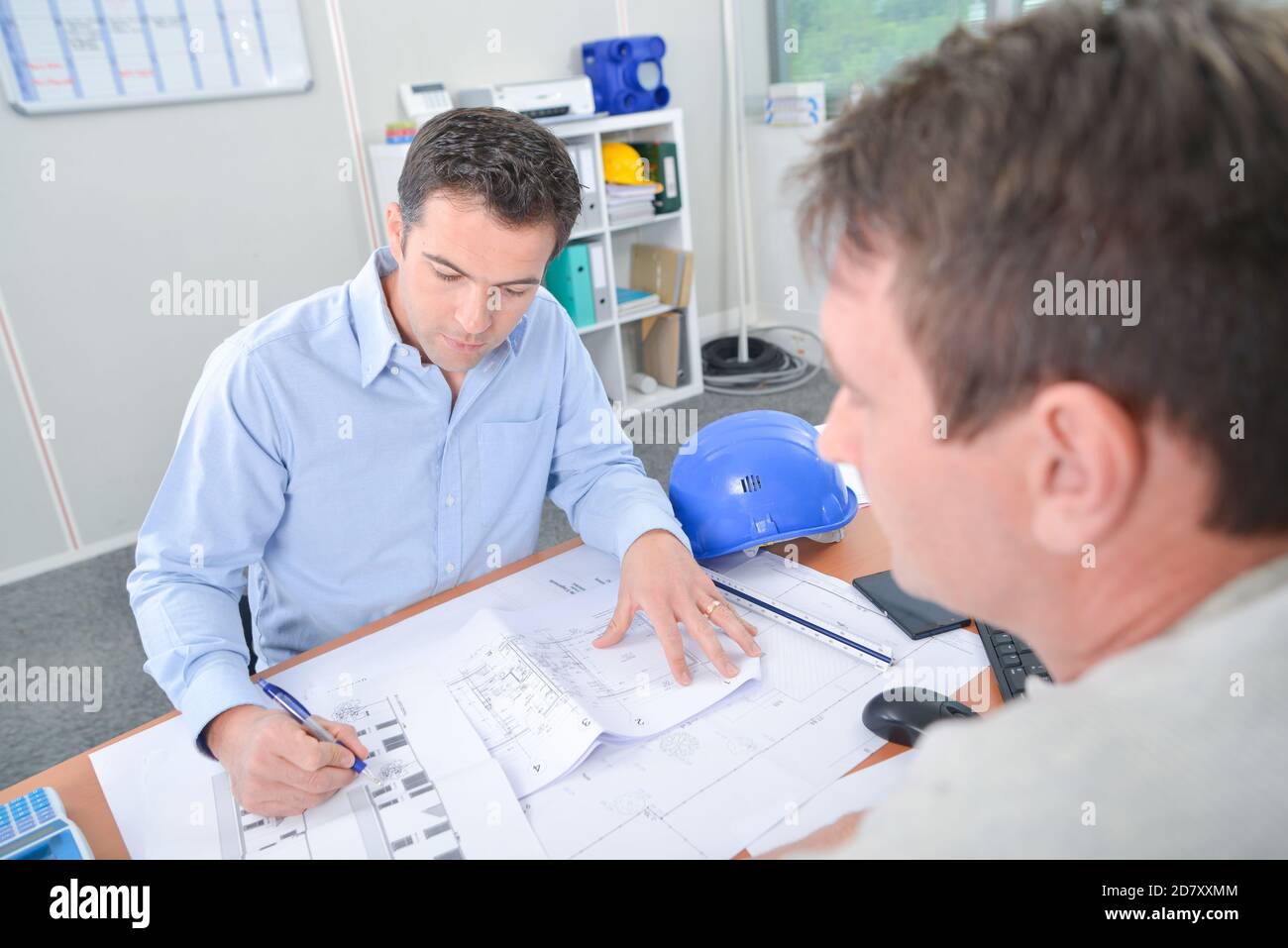 Two men at desk looking at blueprints Stock Photo - Alamy