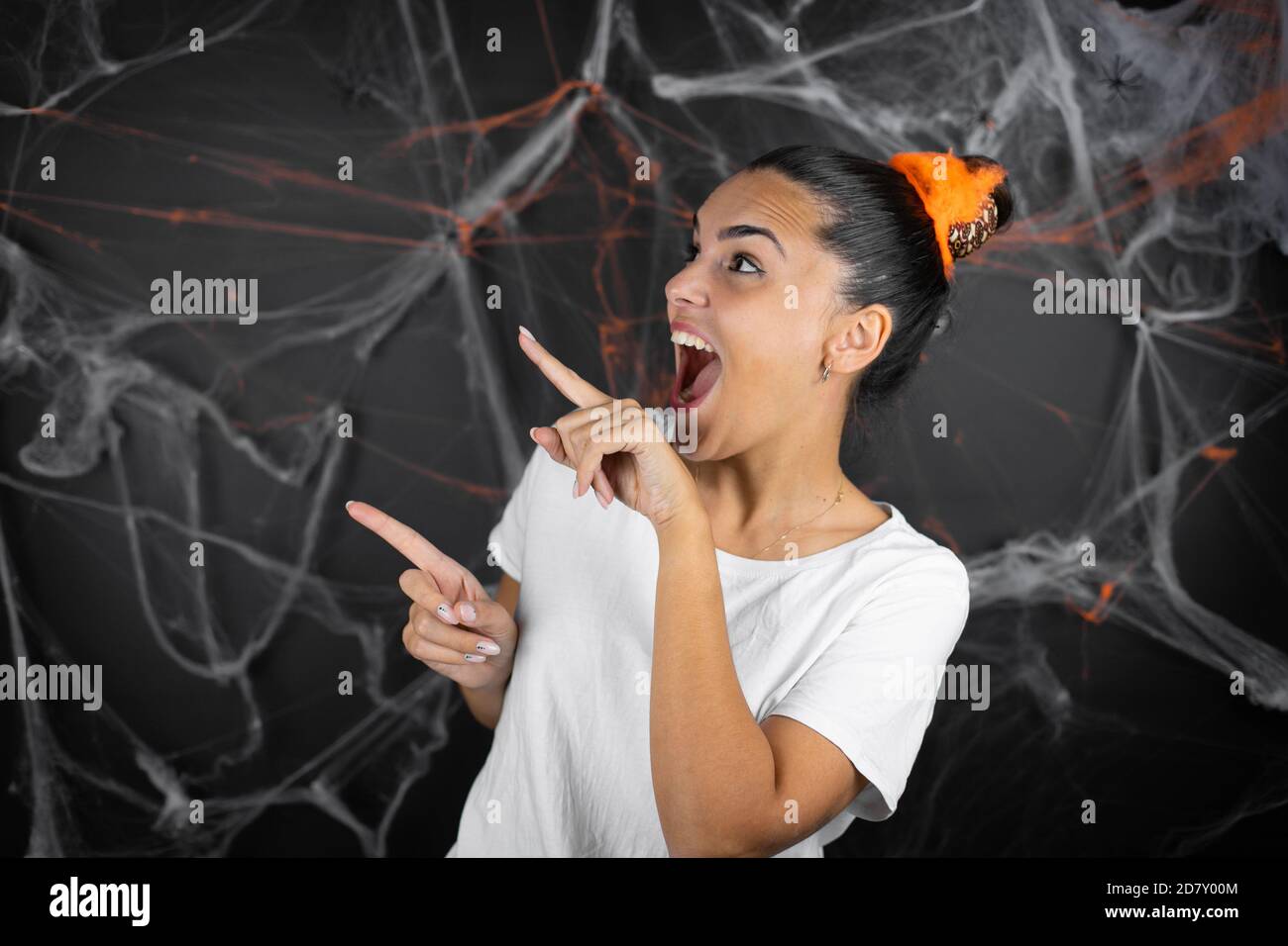 Young beautiful woman over black background with cobwebs and spiders ...