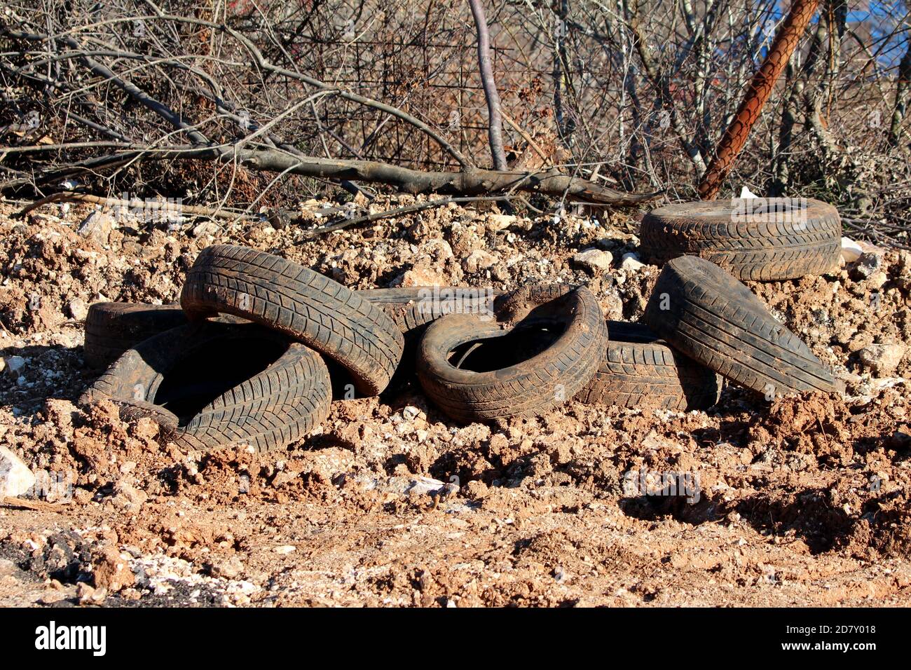Bunch of old heavily used truck tyres covered with dirt left at edge of ...