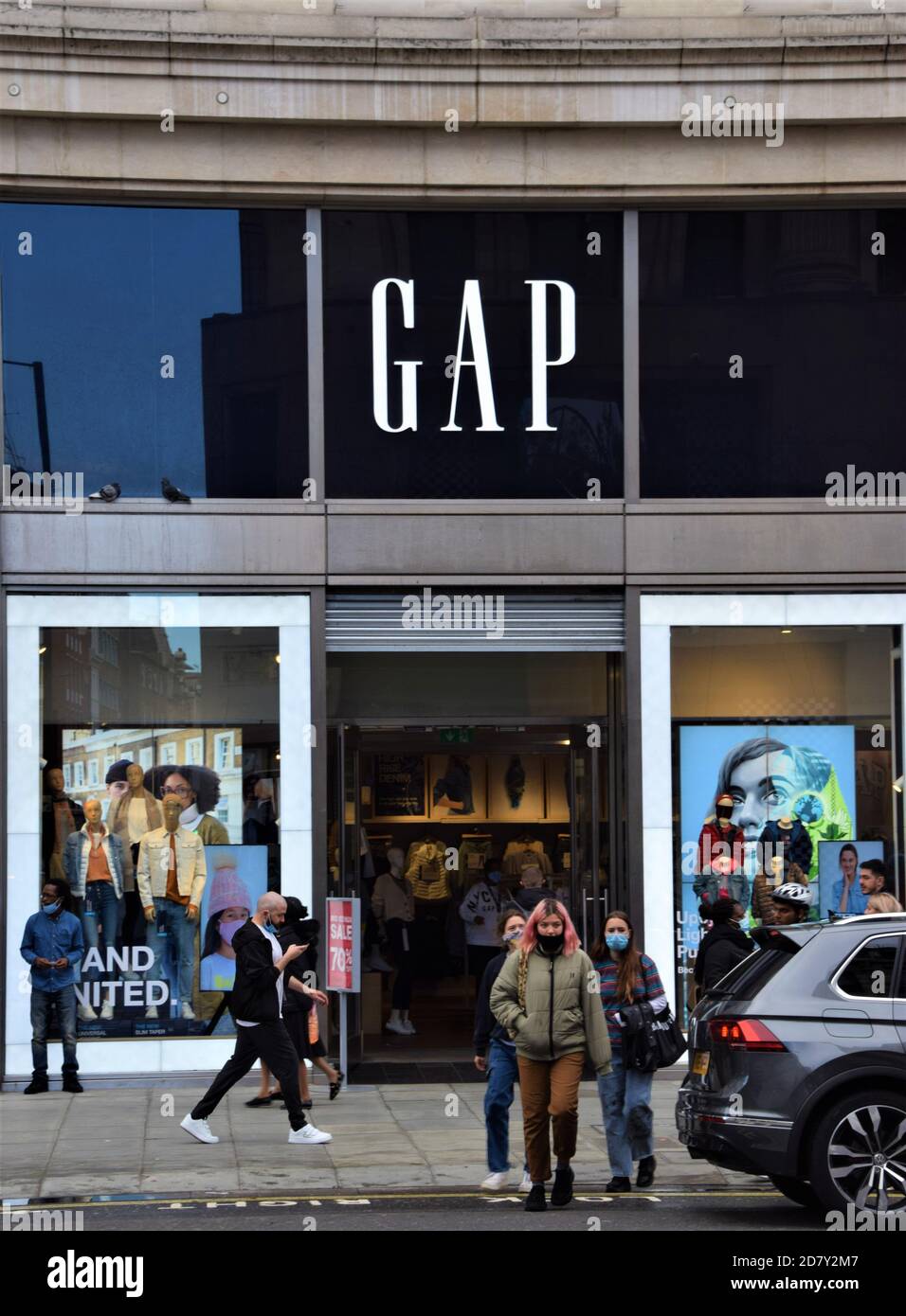 People wearing face masks walk past the Gap store on Oxford Street ...