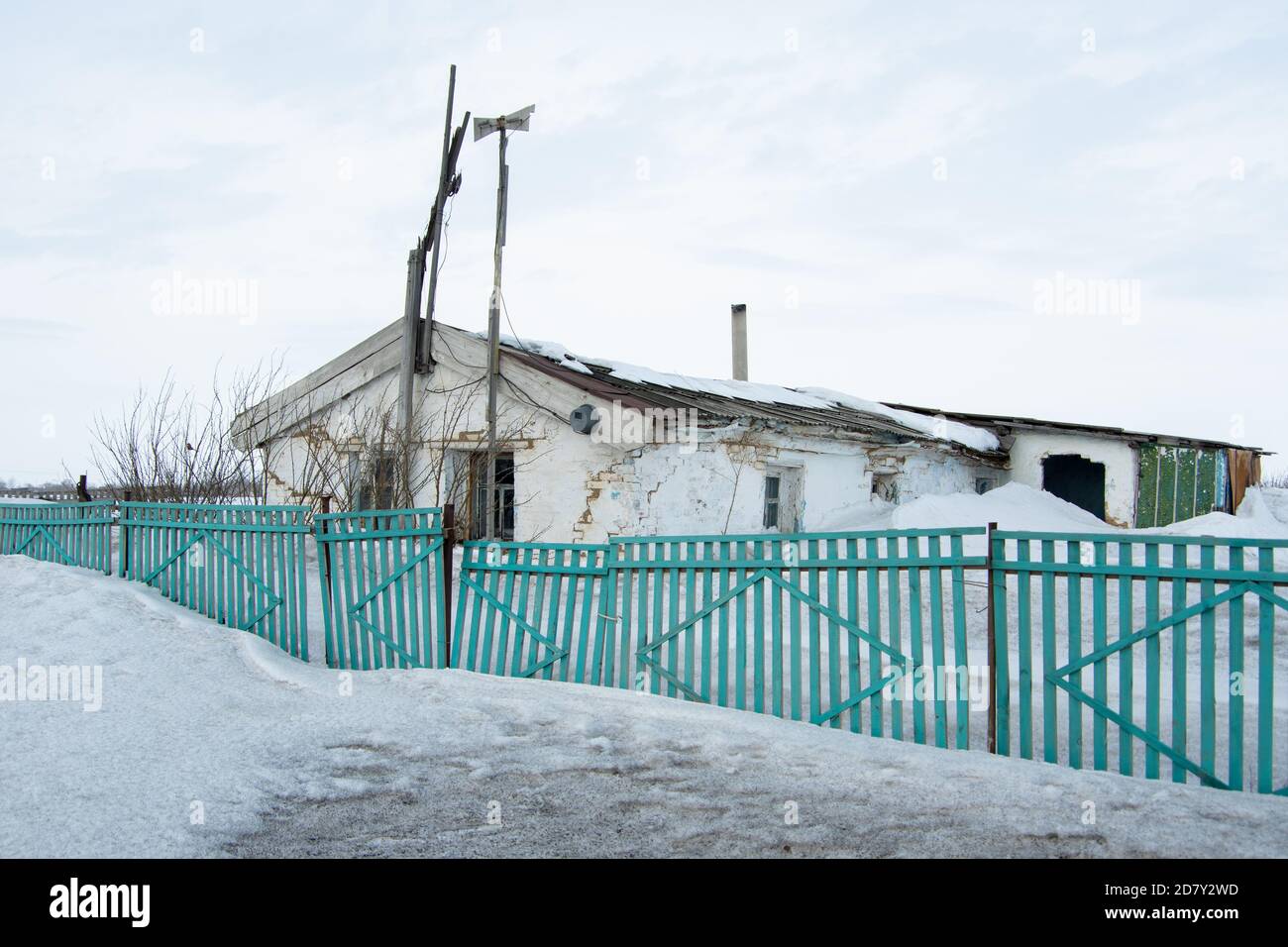 Old village house, dugout behind a blue fence, covered with snow after ...
