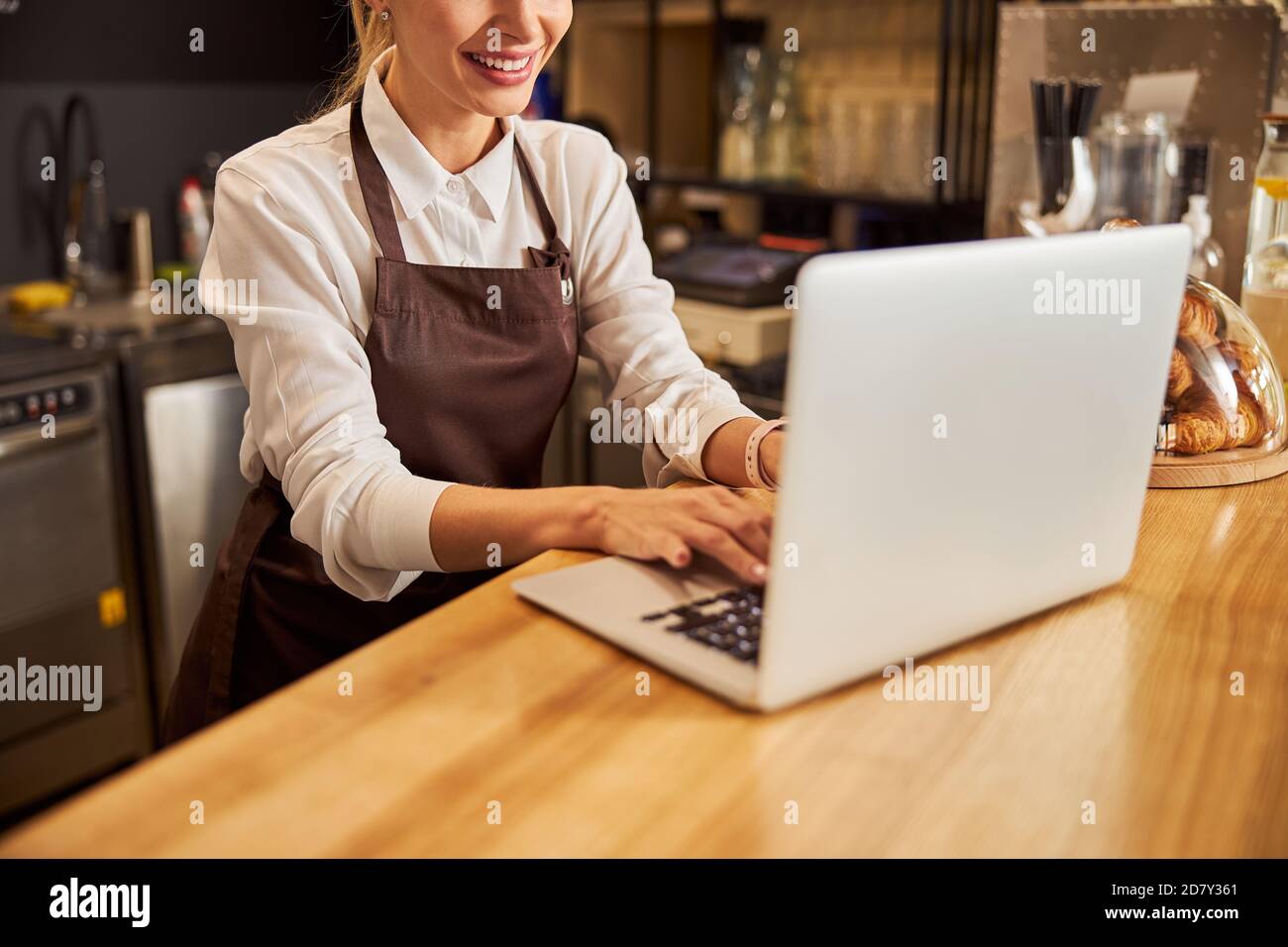 Saleswoman in uniform typing report on the computer in coffee bar Stock ...