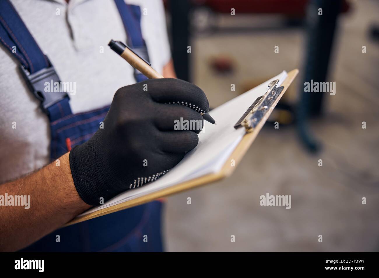 Auto mechanic writing on clipboard at service station Stock Photo - Alamy